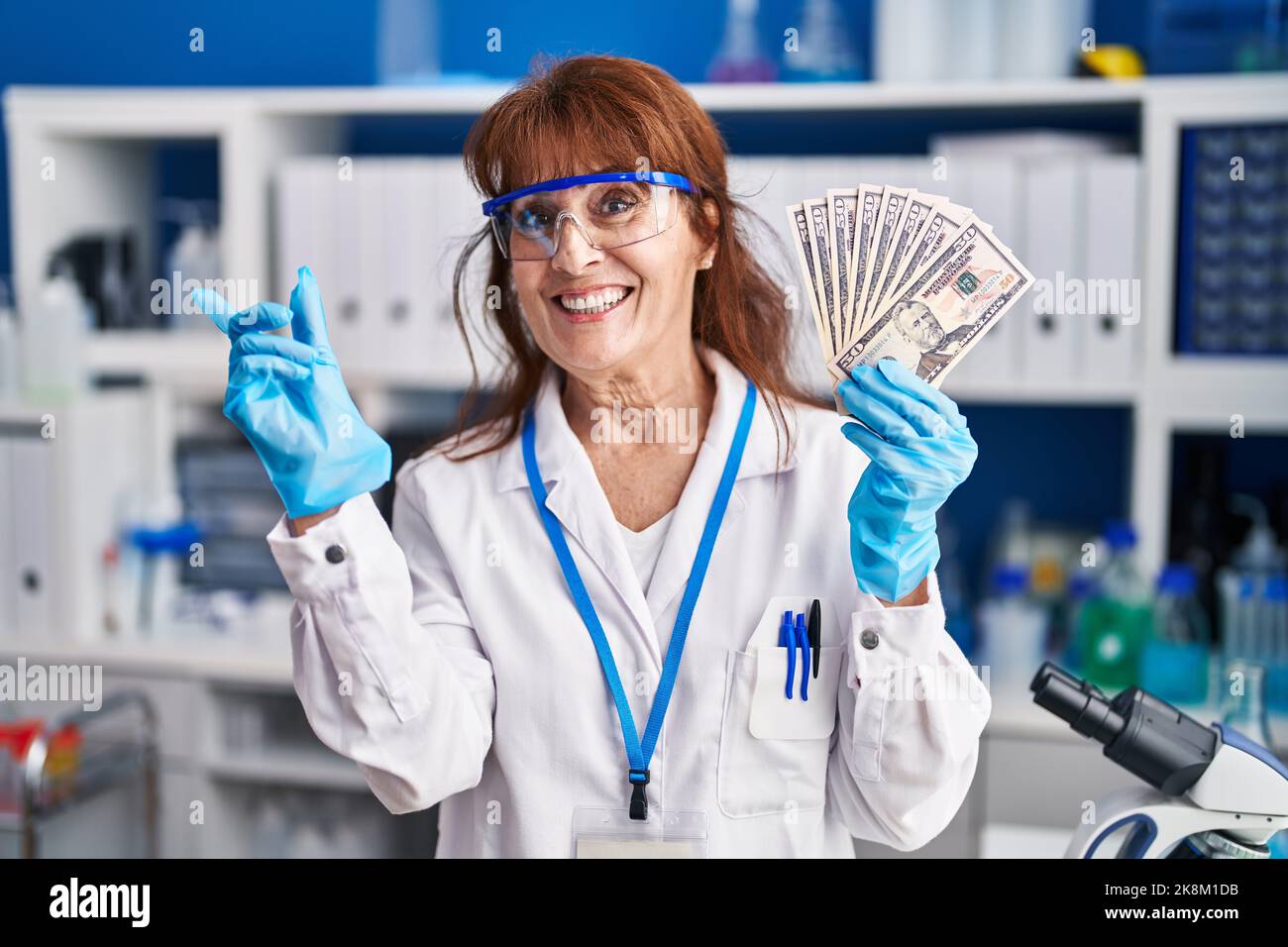 Middle age hispanic woman working at scientist laboratory holding ...