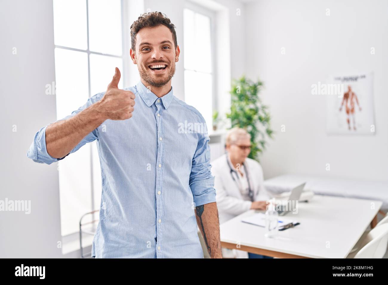 Hispanic man at doctor clinic smiling happy and positive, thumb up ...