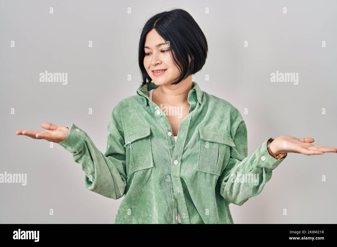 Young asian woman standing over white background smiling showing both ...
