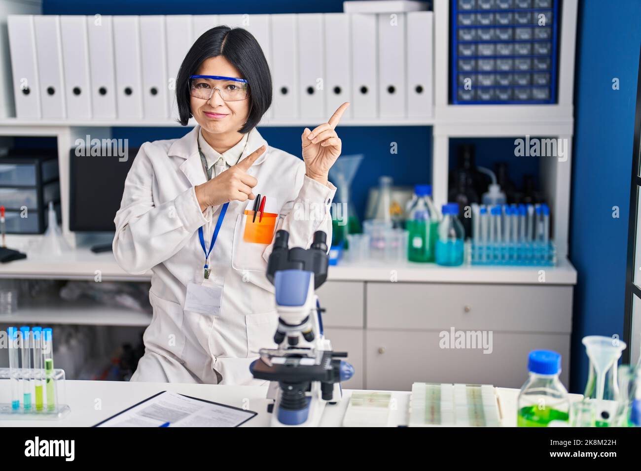 Young asian woman working at scientist laboratory smiling and looking ...