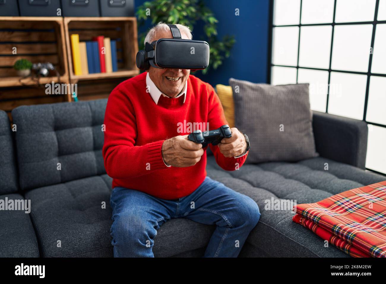 Senior man playing video game using virtual reality goggles at home ...