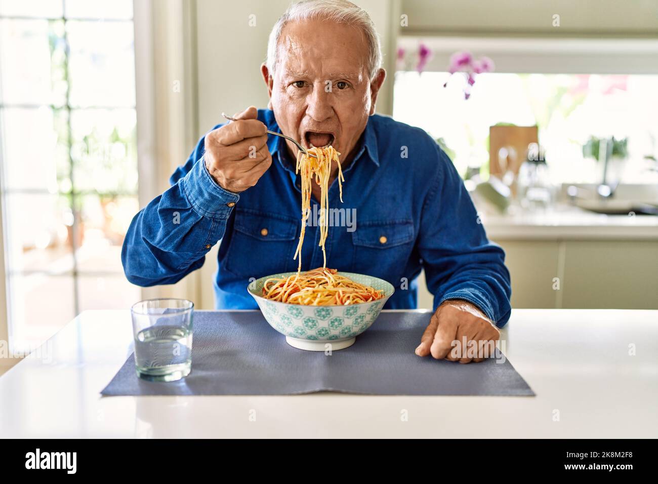 Senior man eating spaghetti at kitchen Stock Photo - Alamy