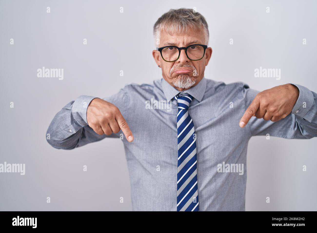 Hispanic business man with grey hair wearing glasses pointing down ...