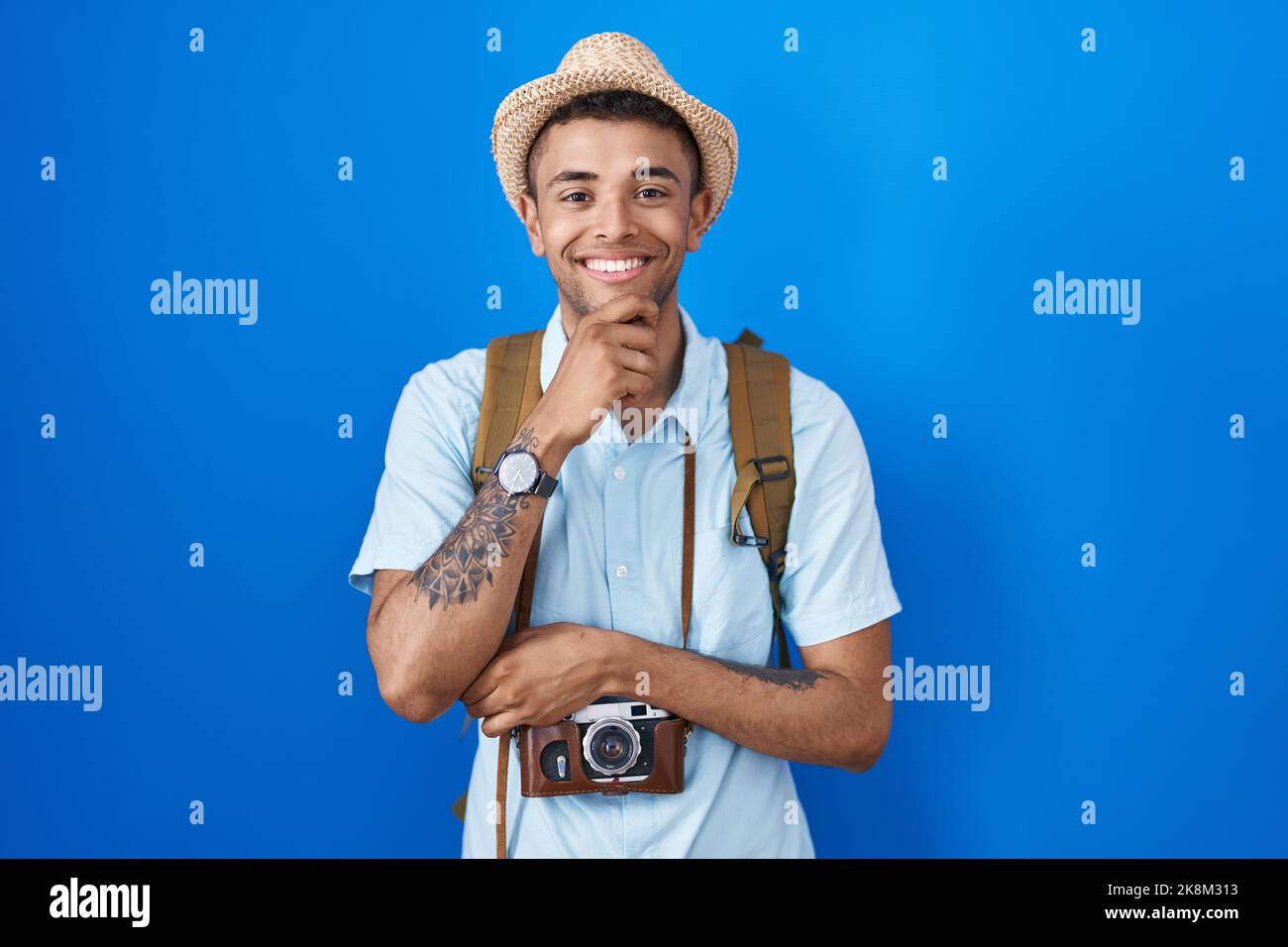 Brazilian young man holding vintage camera looking confident at the ...