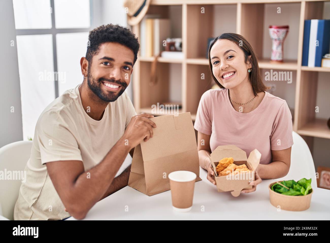 Man And Woman Couple Sitting On Table Eating Take Away Food At Home