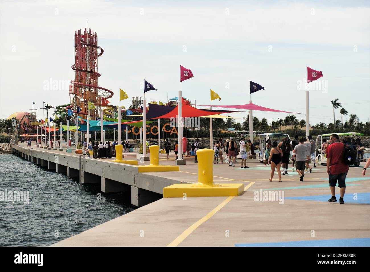 A group of people walking on busy wooden dock with colorful attractions ...