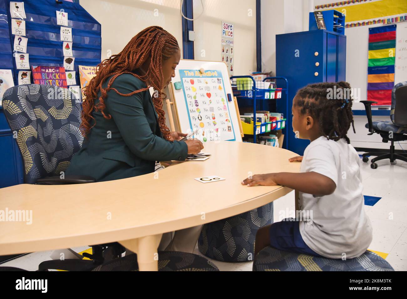 An African American Black teacher teaching young black student in the ...