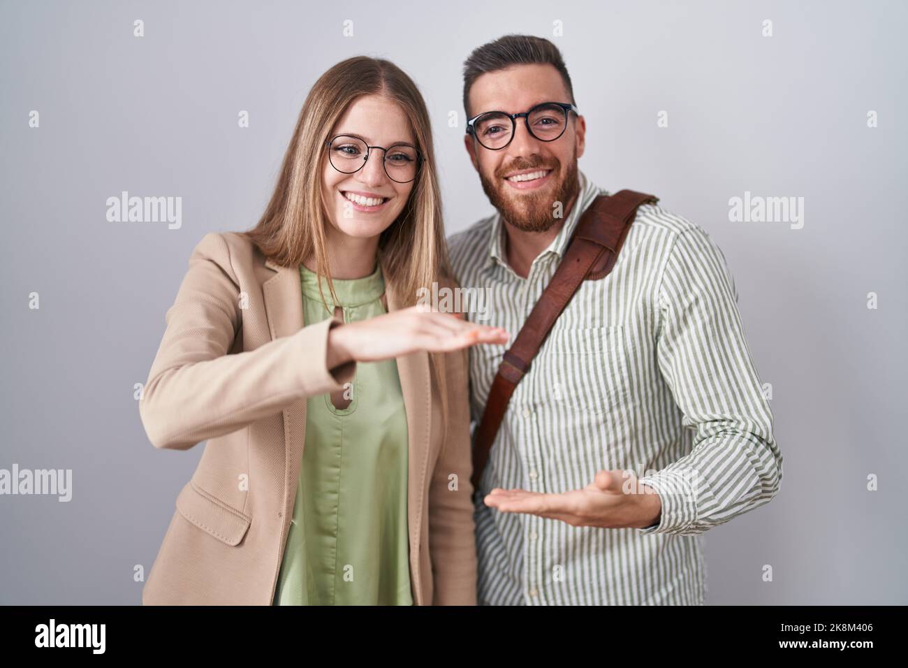 Young couple standing over white background gesturing with hands ...
