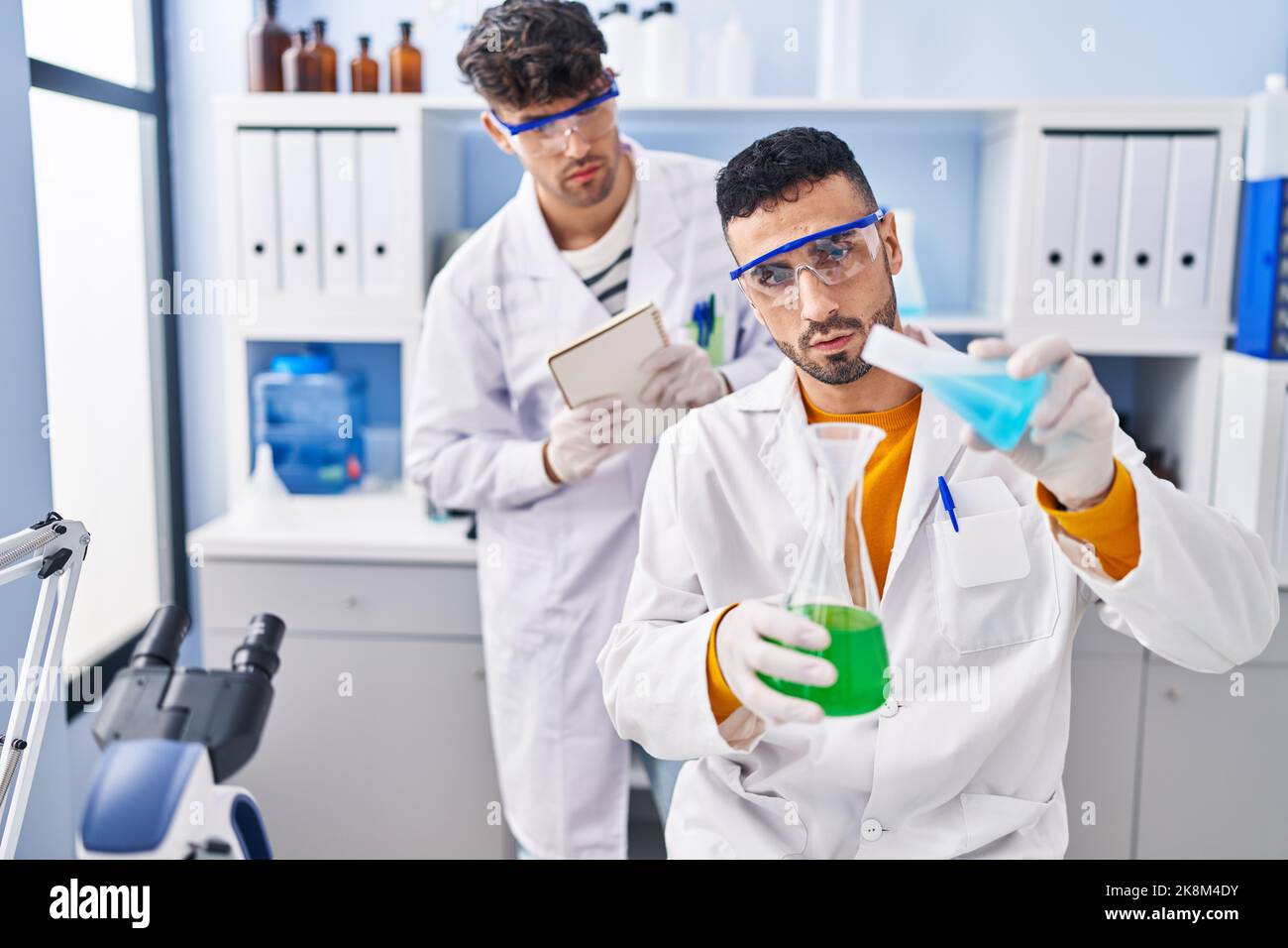 Two man scientists measuring liquid at laboratory Stock Photo - Alamy