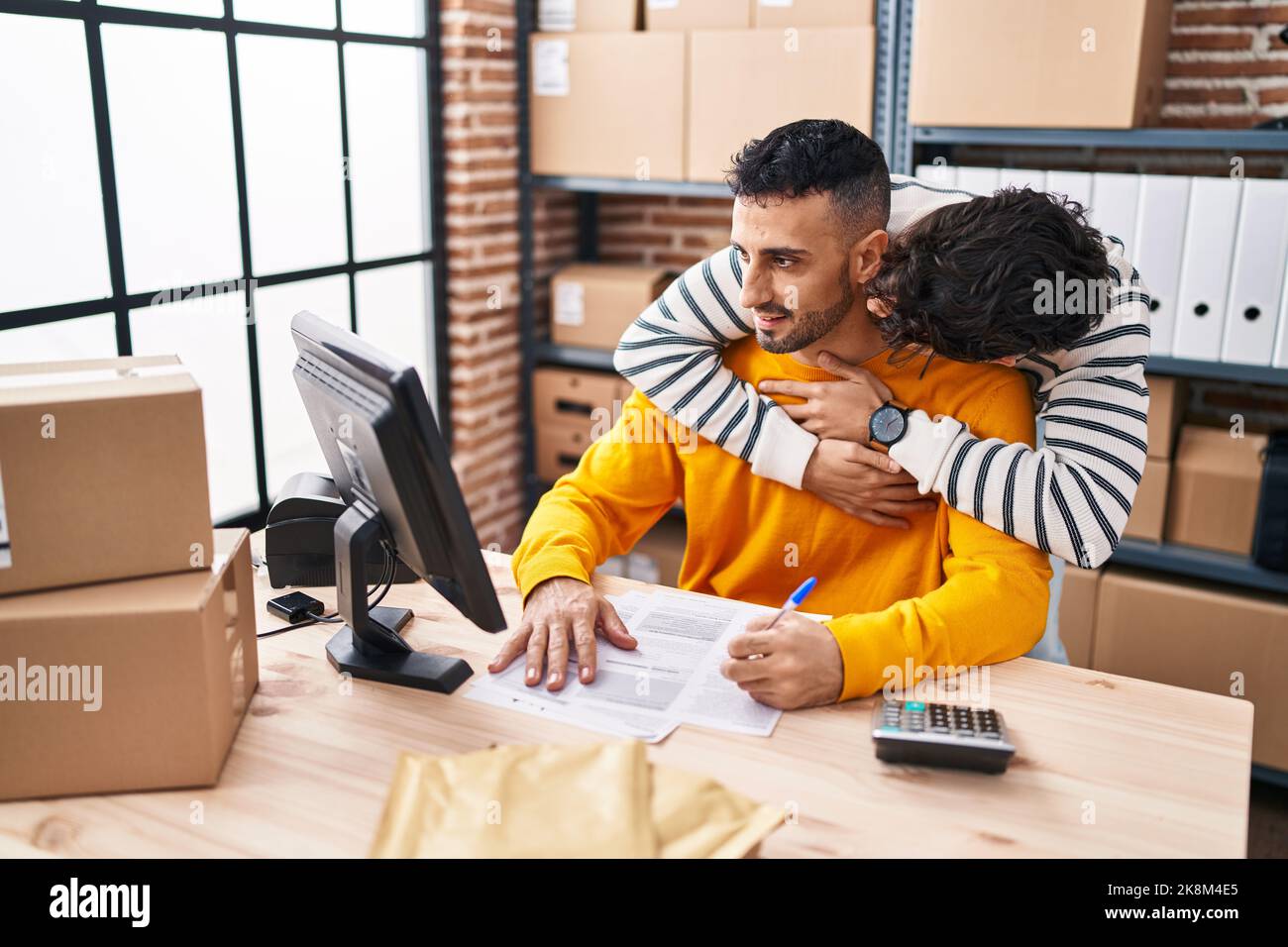Two man ecommerce business workers hugging each other working at office ...