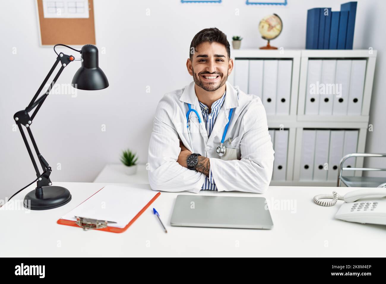 Handsome hispanic man working as doctor at medical consultation Stock ...
