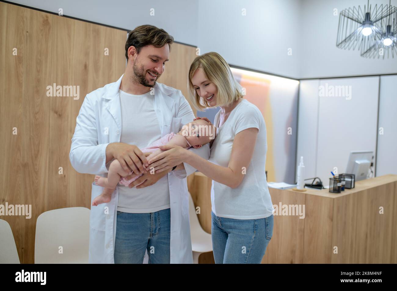 Pediatric doctor examining the newborn supervised by the female parent ...