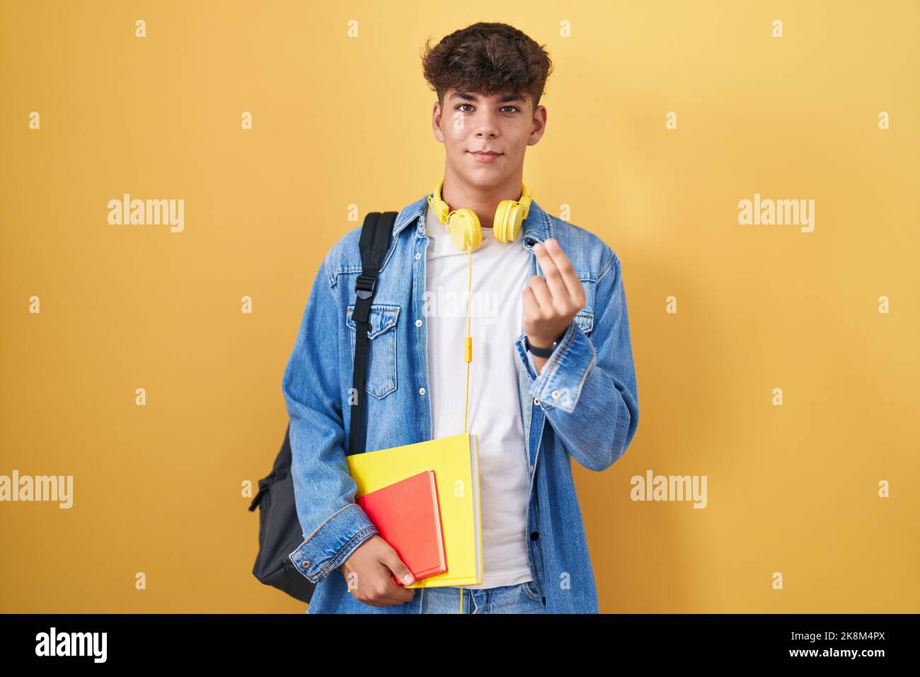 Hispanic teenager wearing student backpack and holding books doing ...