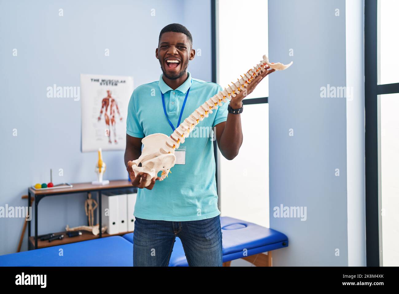 African american man holding anatomical model of spinal column ...