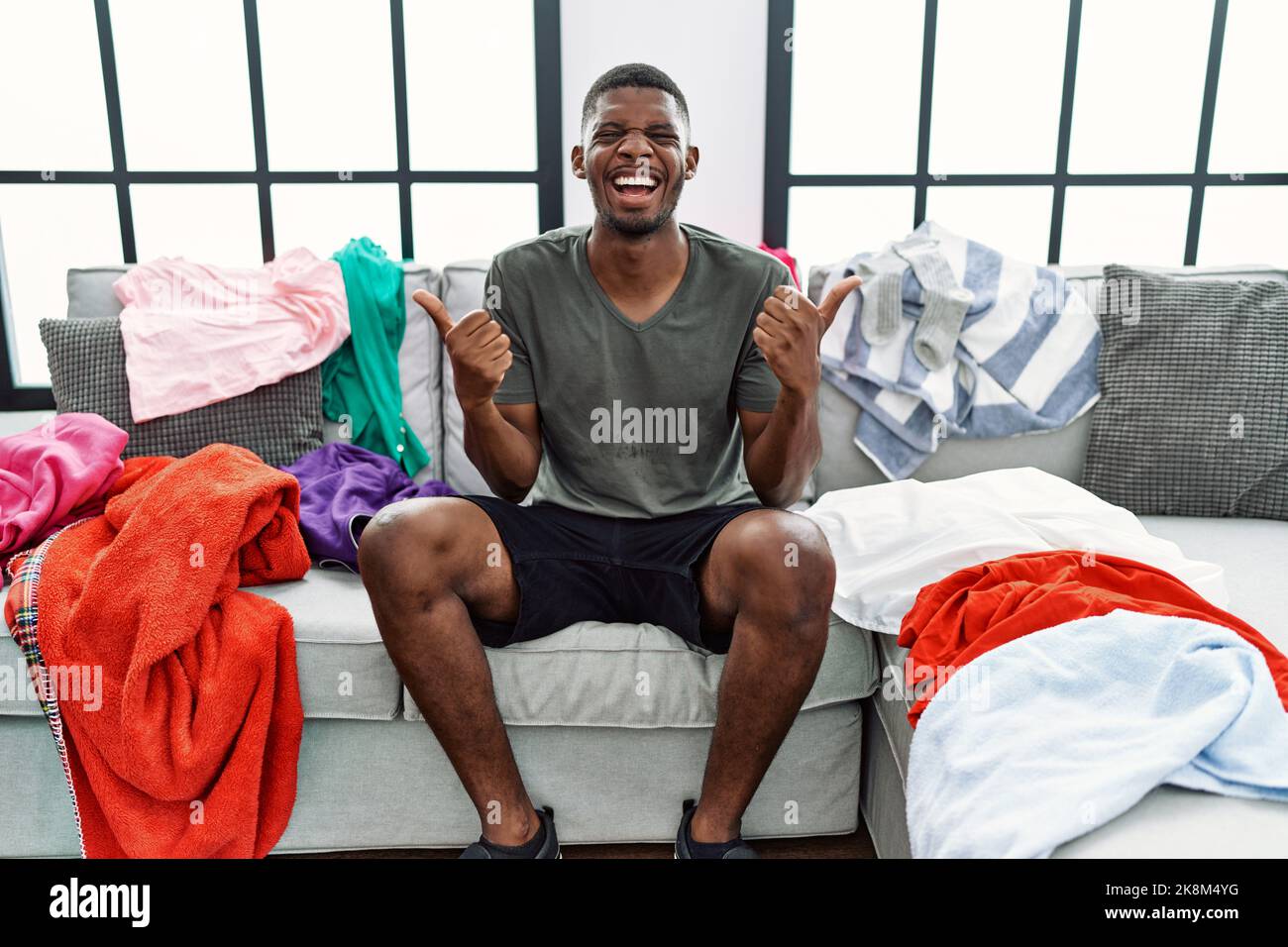 Young african american man sitting on the sofa with dirty laundry ...