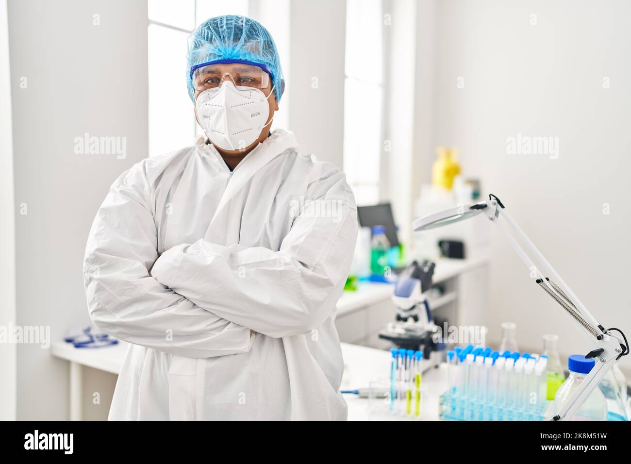 Young latin man scientist wearing covid protection uniform standing ...