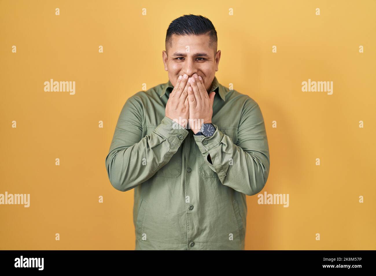 Hispanic young man standing over yellow background laughing and ...