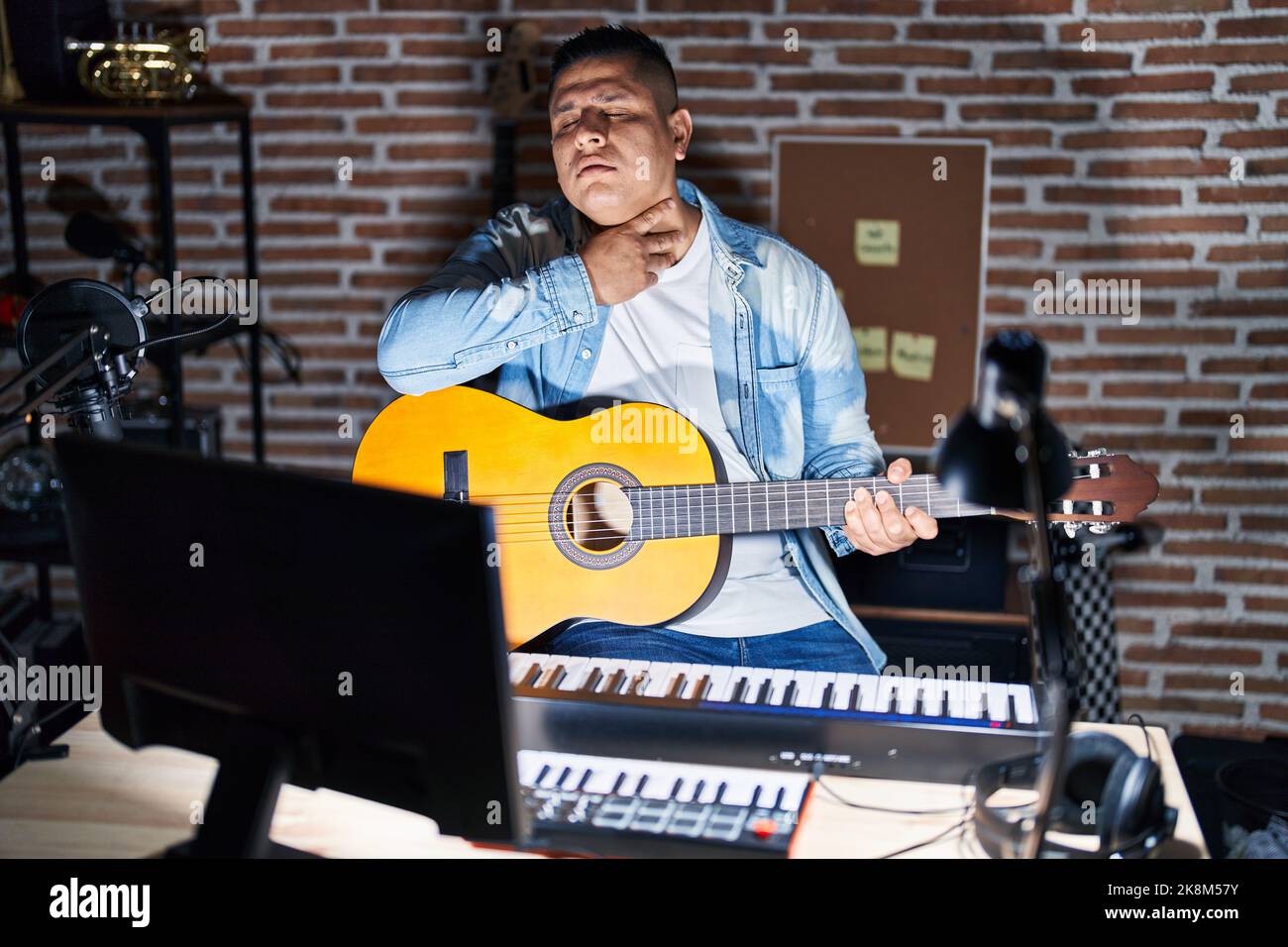 Hispanic young man playing classic guitar at music studio touching ...
