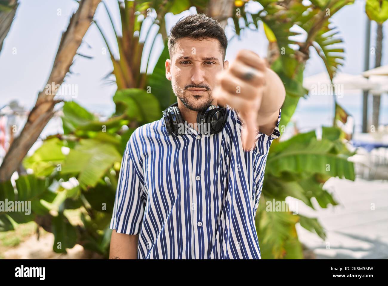 Young handsome man listening to music using headphones outdoors looking ...