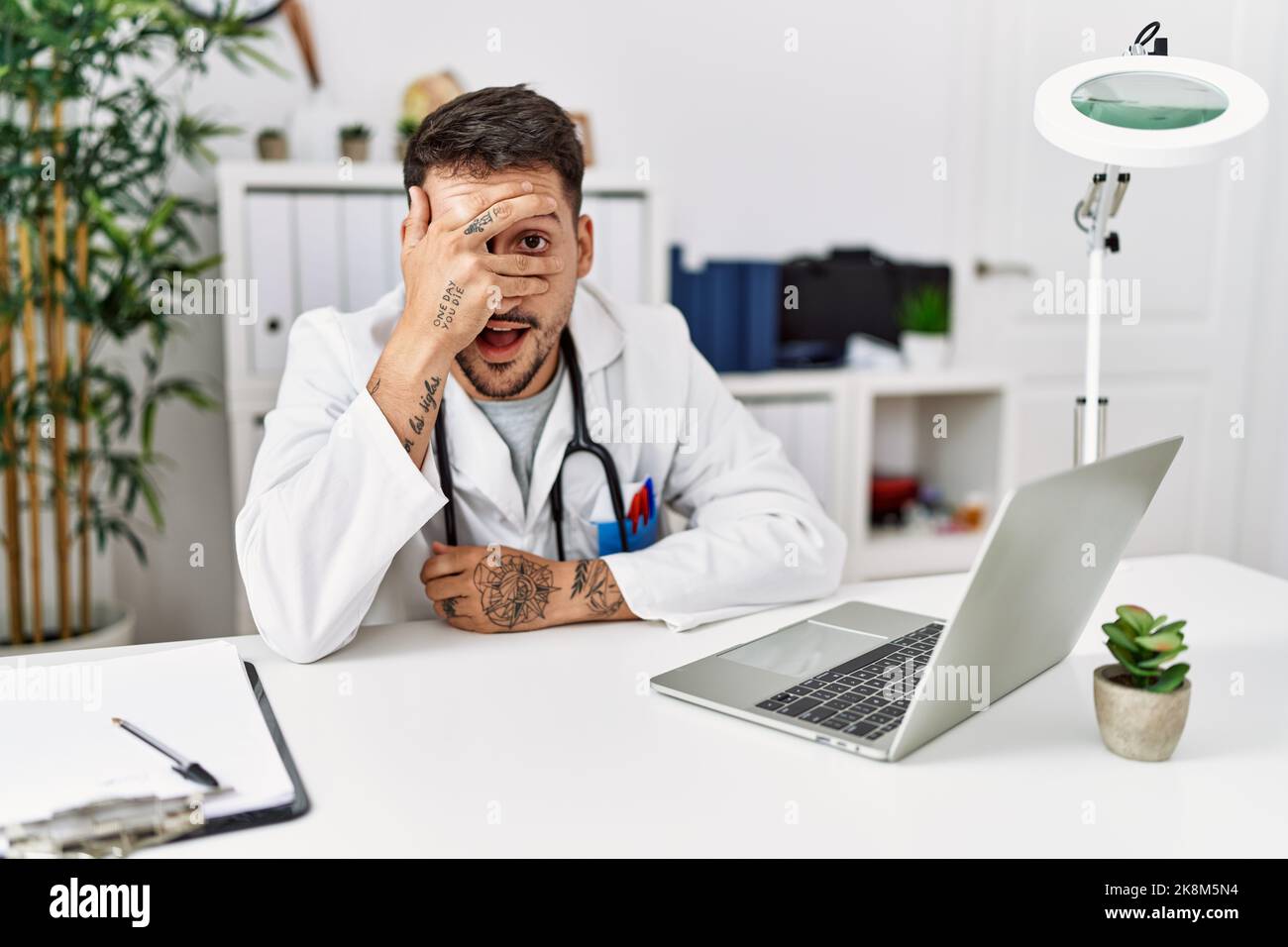 Young doctor working at the clinic using computer laptop peeking in ...