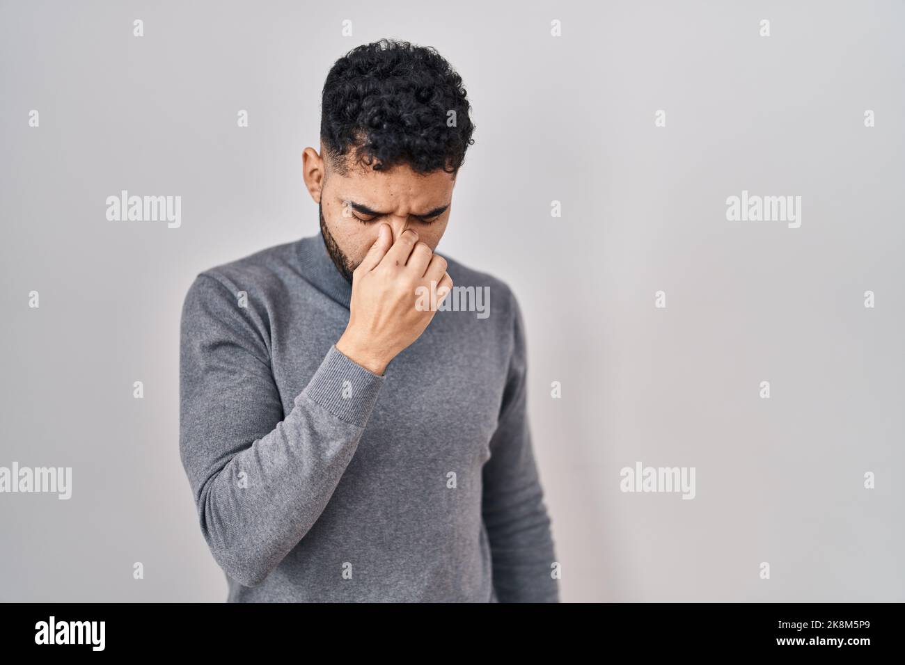 Hispanic man with beard standing over white background tired rubbing ...