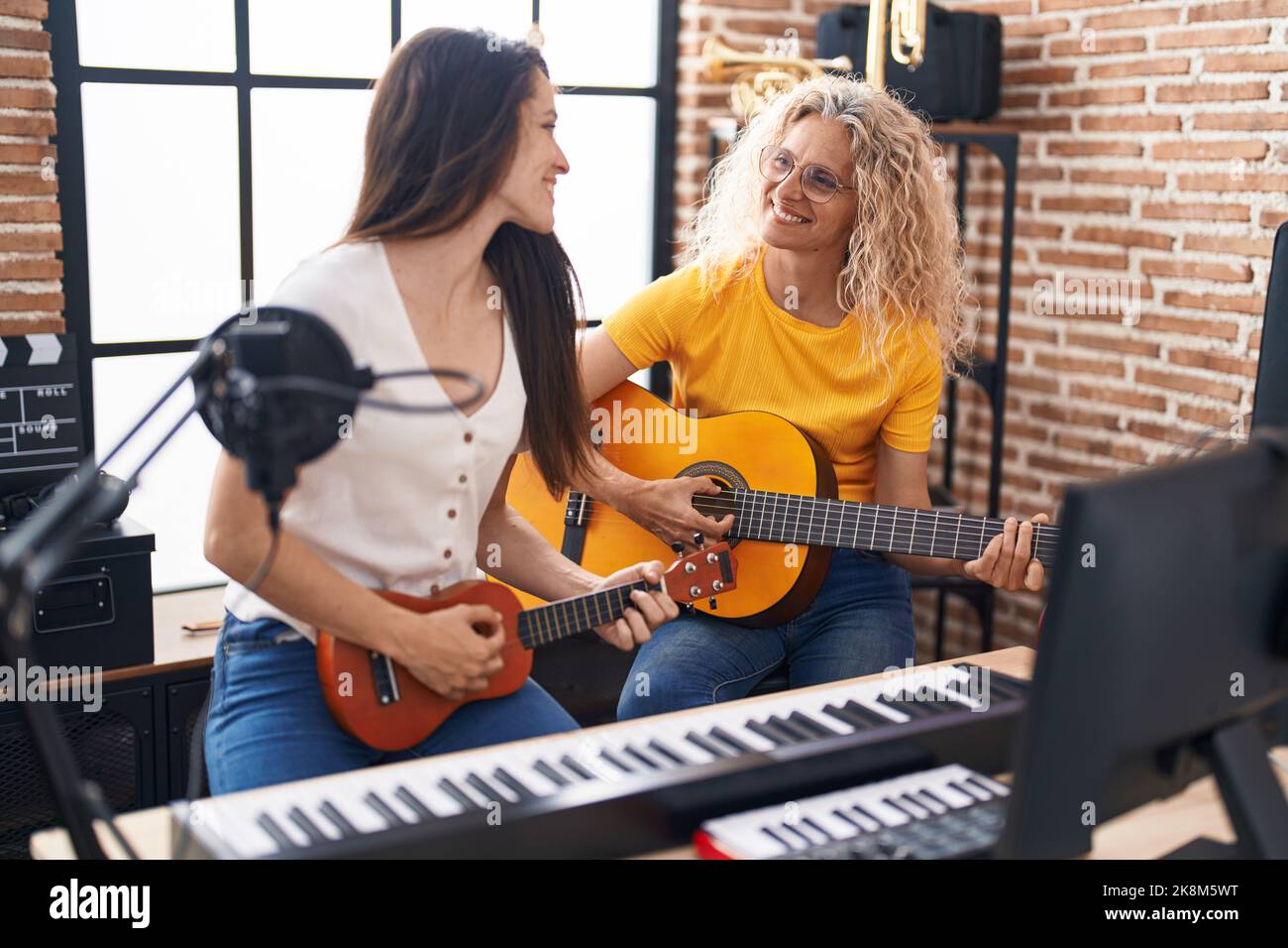 Two women musicians playing classical guitar and ukulele at music ...