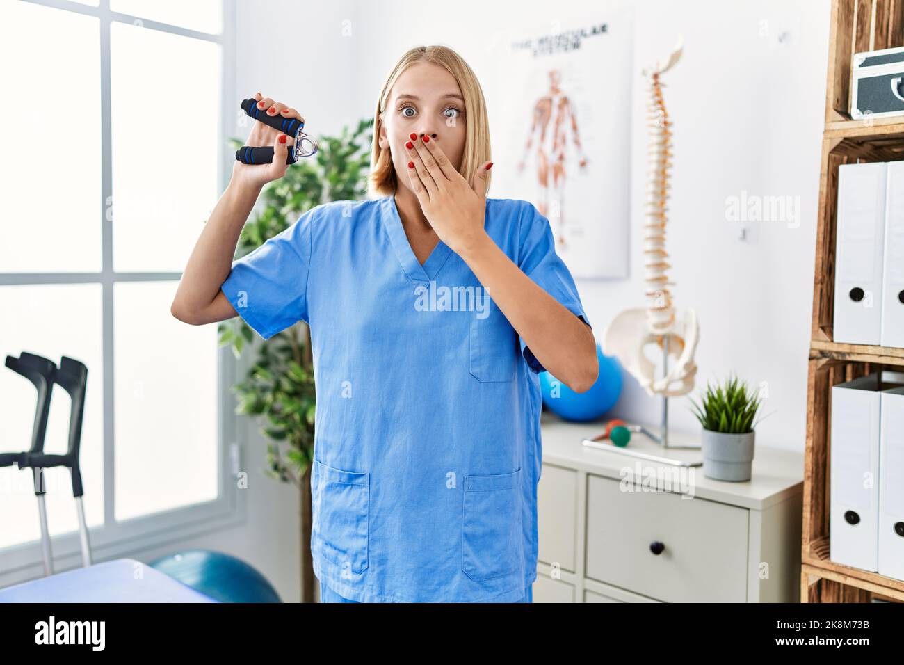 Young caucasian physiotherapist woman holding hand grip to train muscle ...