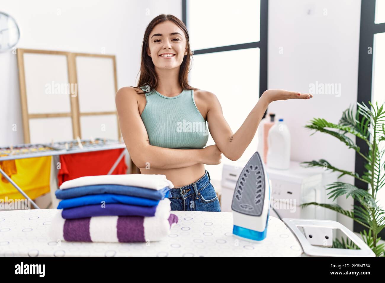 Young hispanic woman ironing clothes at laundry room smiling cheerful ...