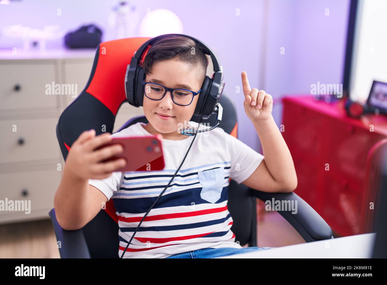Young hispanic kid playing video games with smartphone smiling with an ...