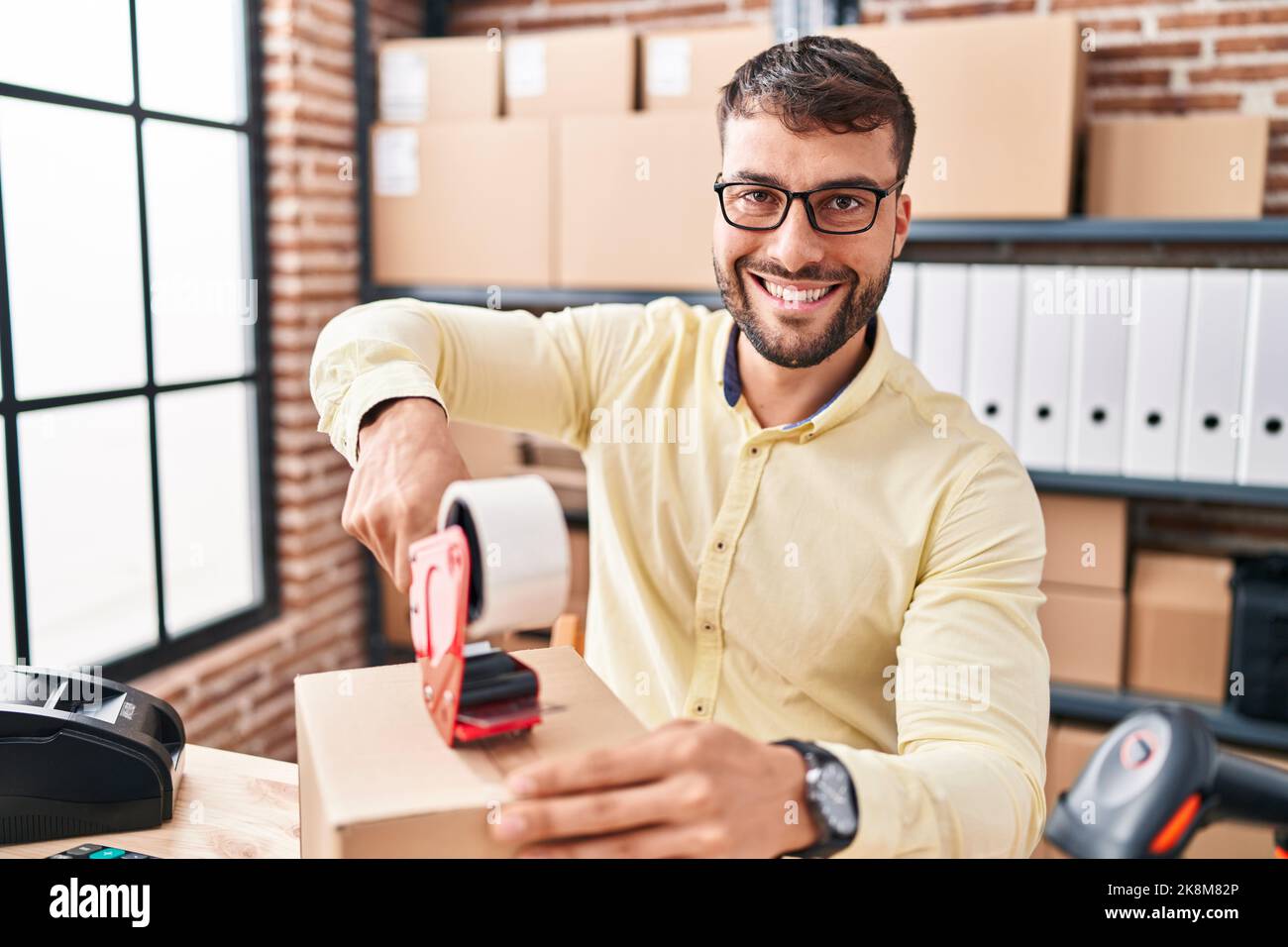 Young hispanic man ecommerce business worker packing cardboard box at ...