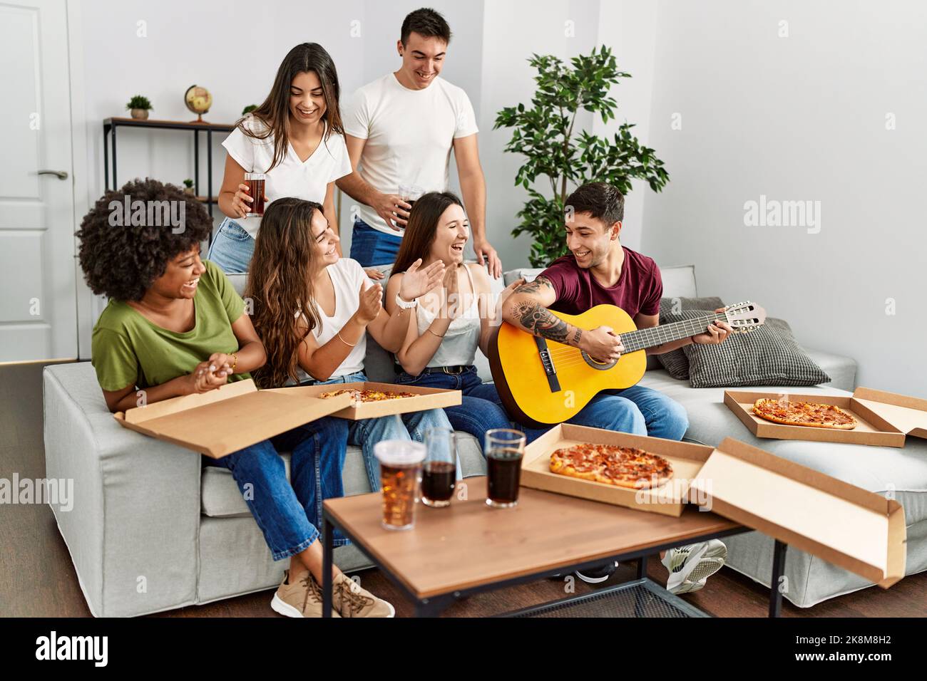 Group of young friends having party eating italian pizza and playing ...