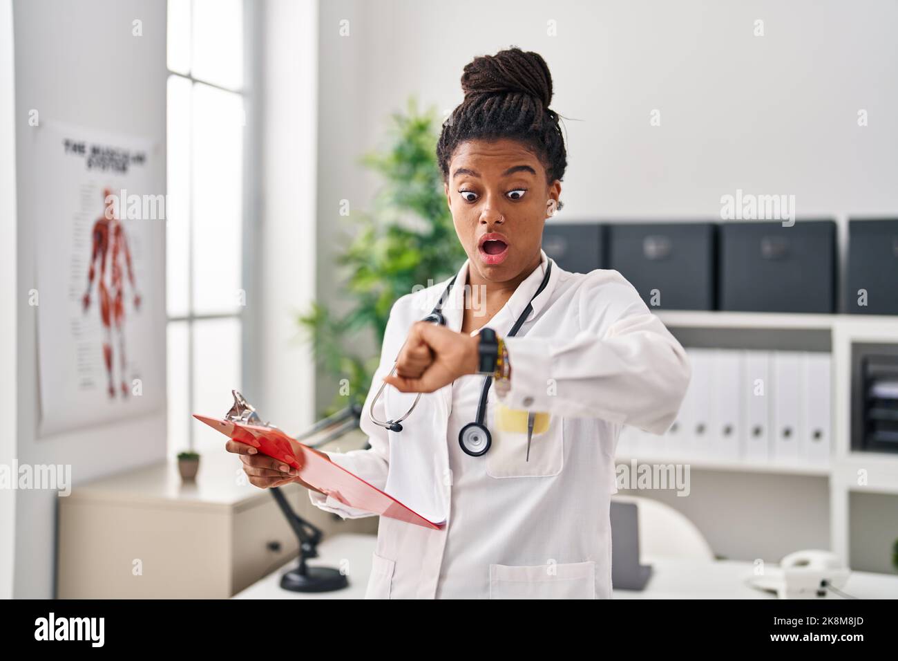 Young african american with braids wearing doctor uniform looking at ...