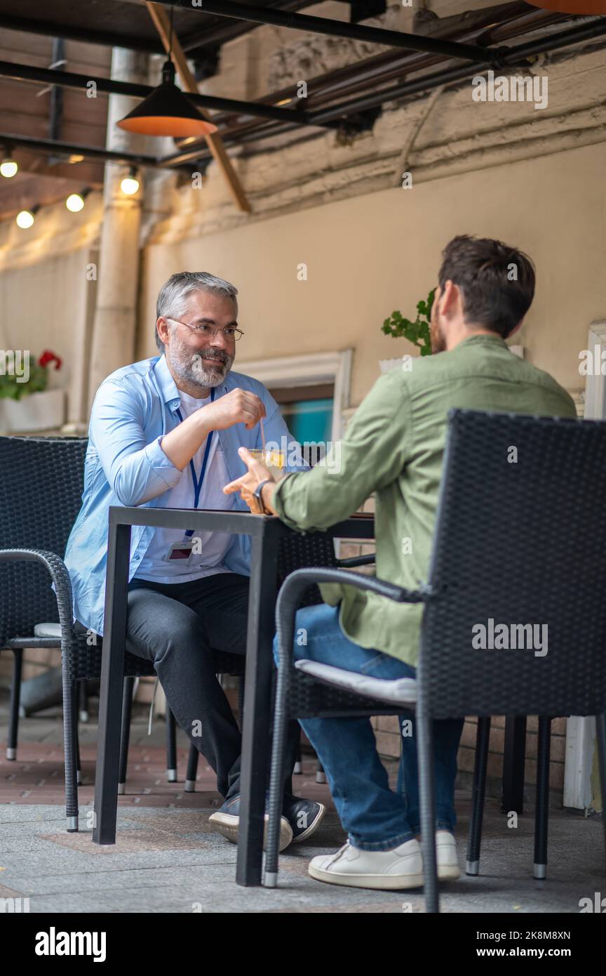 Two men sitting in the cafe and having an interesting conversation ...