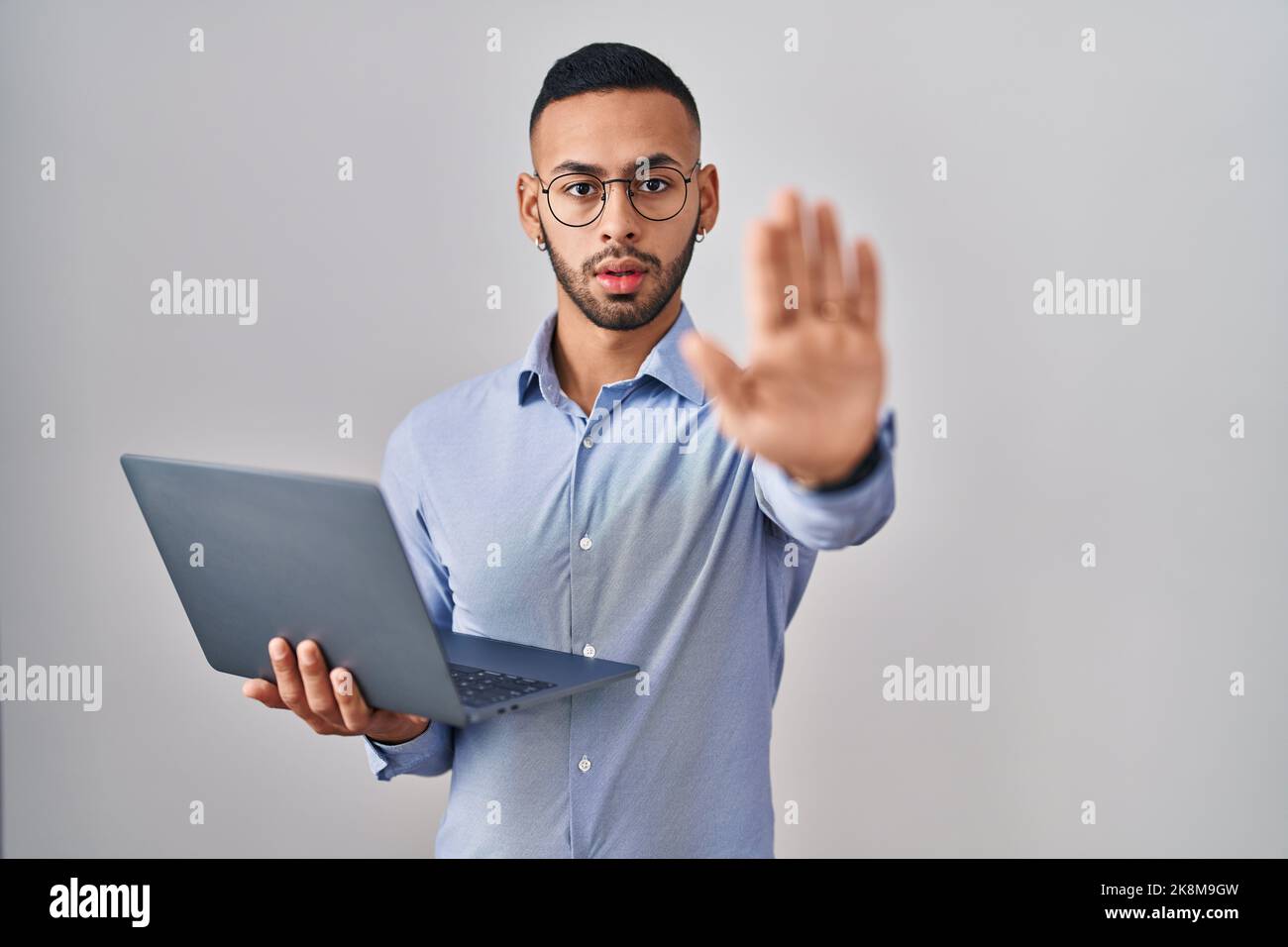 Young hispanic man working using computer laptop doing stop sing with ...
