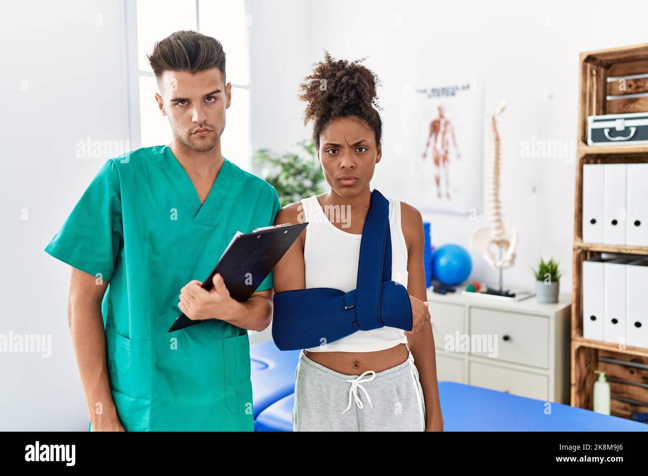 Physiotherapist working with patient wearing arm on sling at ...