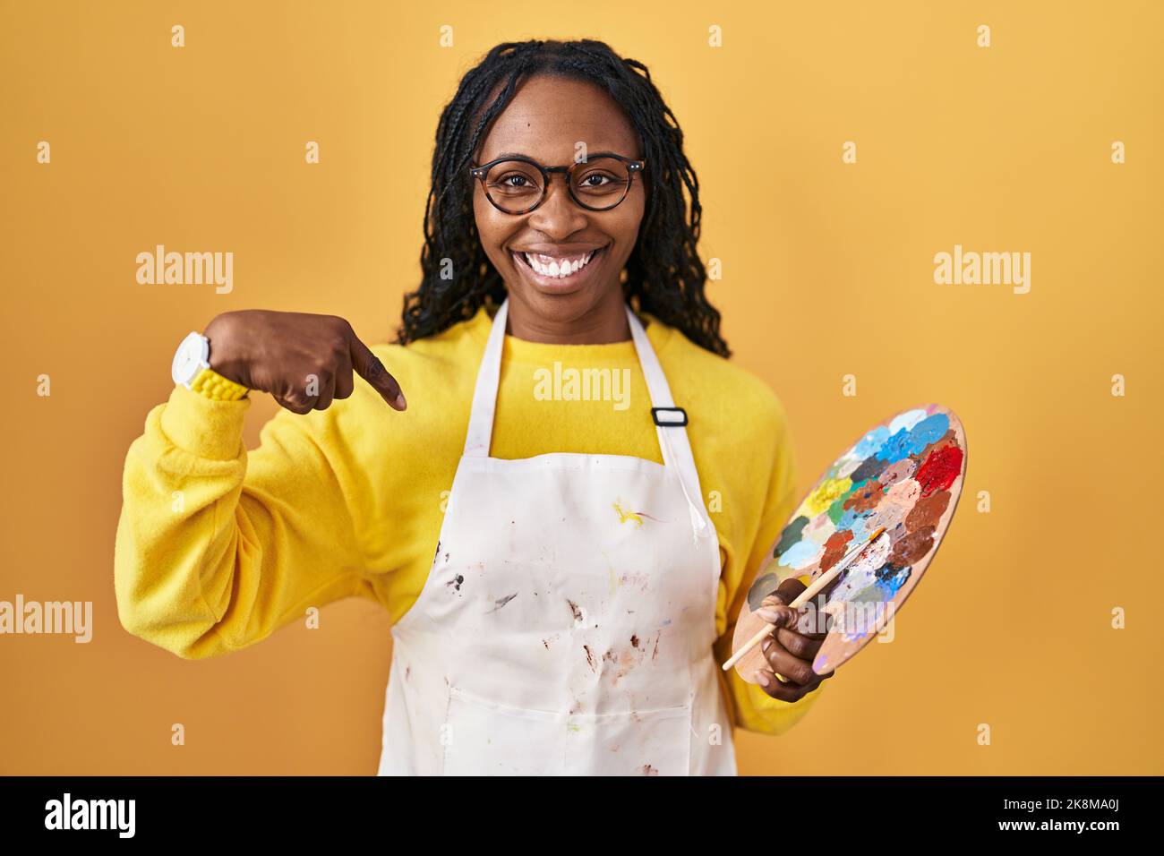 African woman holding painter palette looking confident with smile on ...