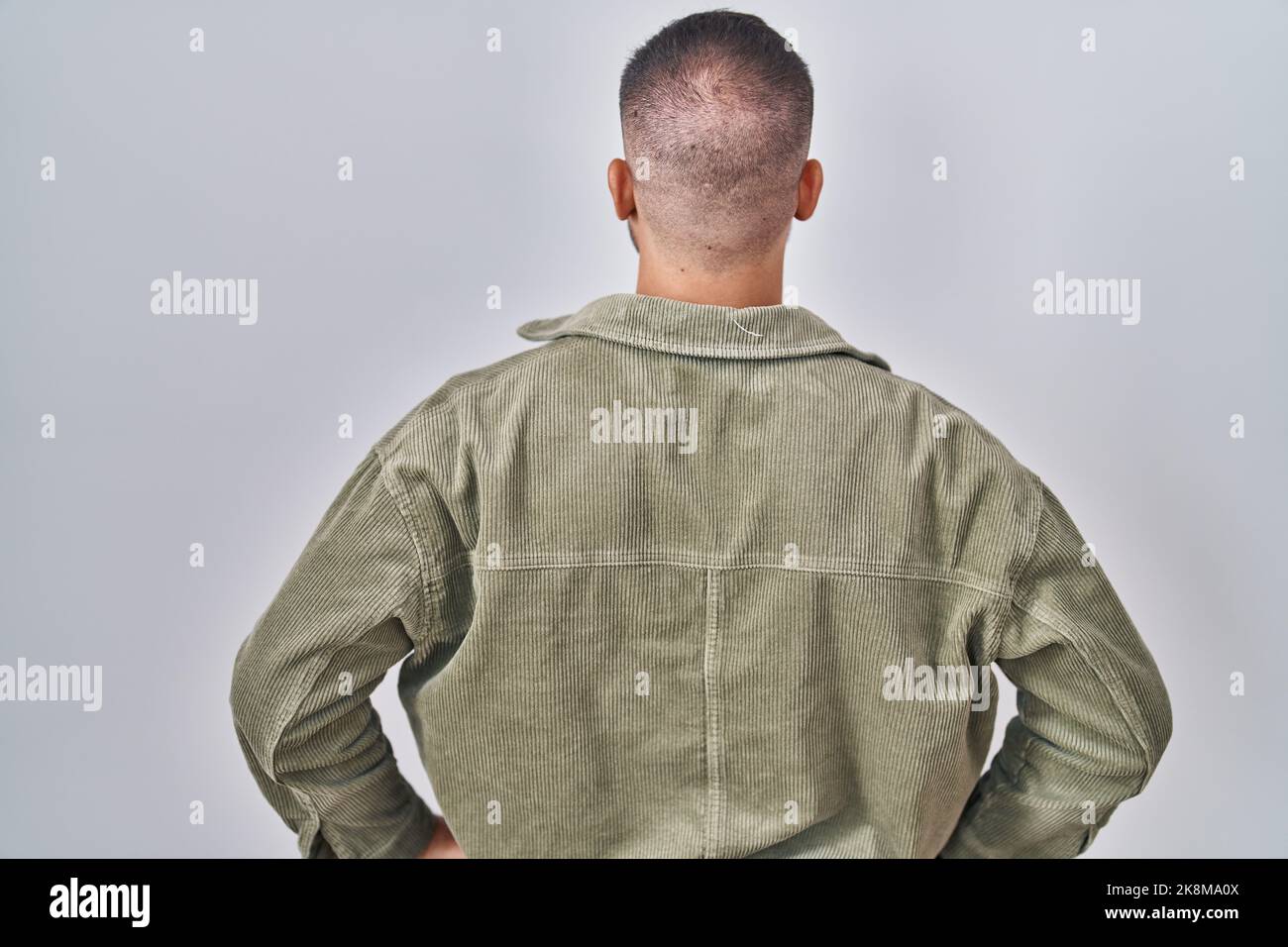 Young hispanic man standing over isolated background standing backwards ...