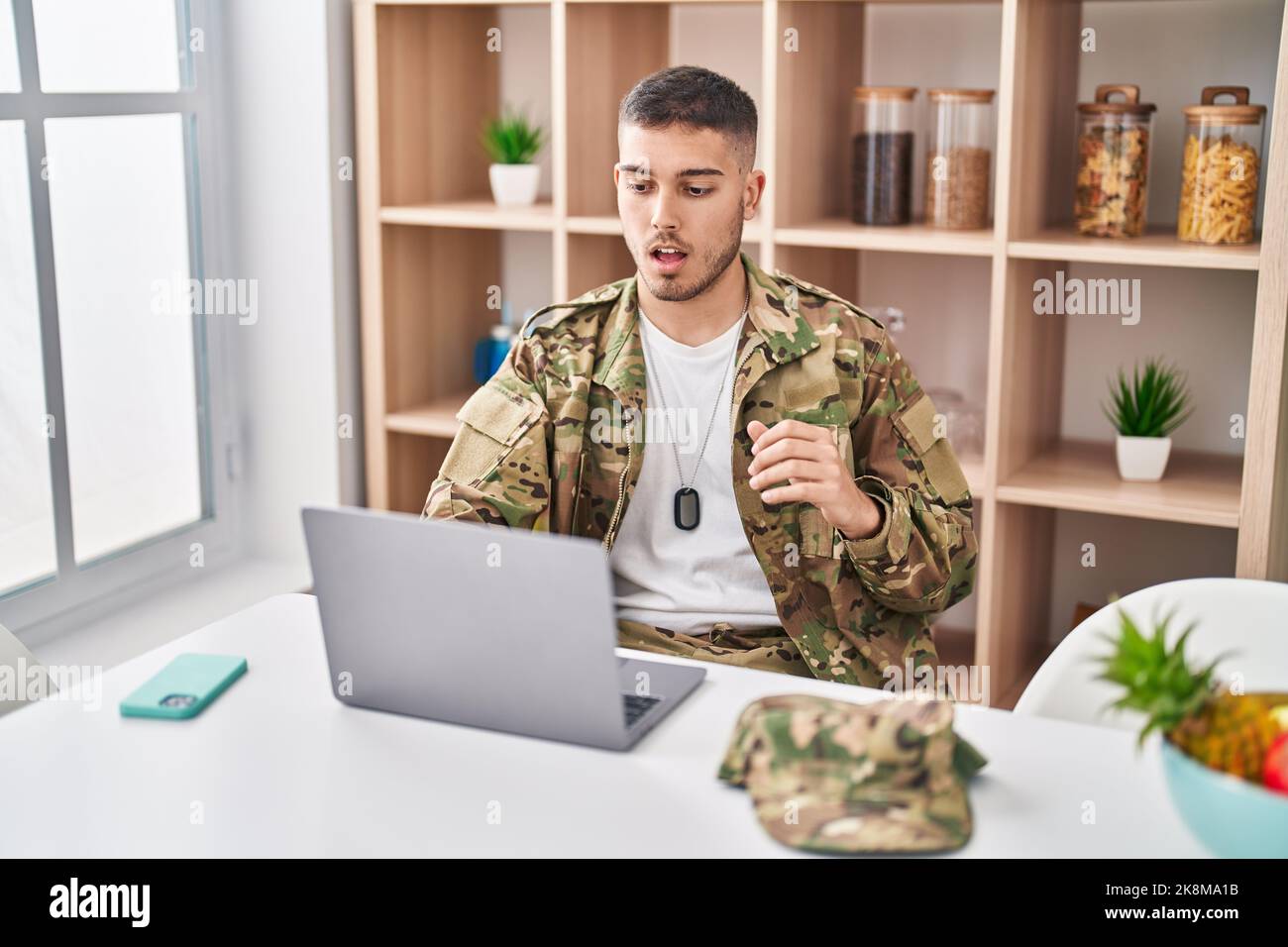 Young hispanic man wearing camouflage army uniform doing video call ...