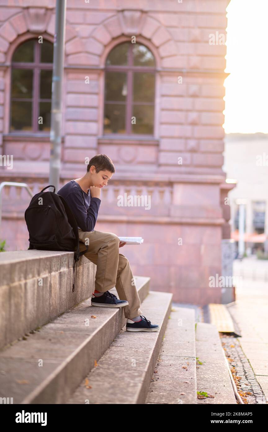 Concentrated teenager perusing a textbook outdoors Stock Photo - Alamy