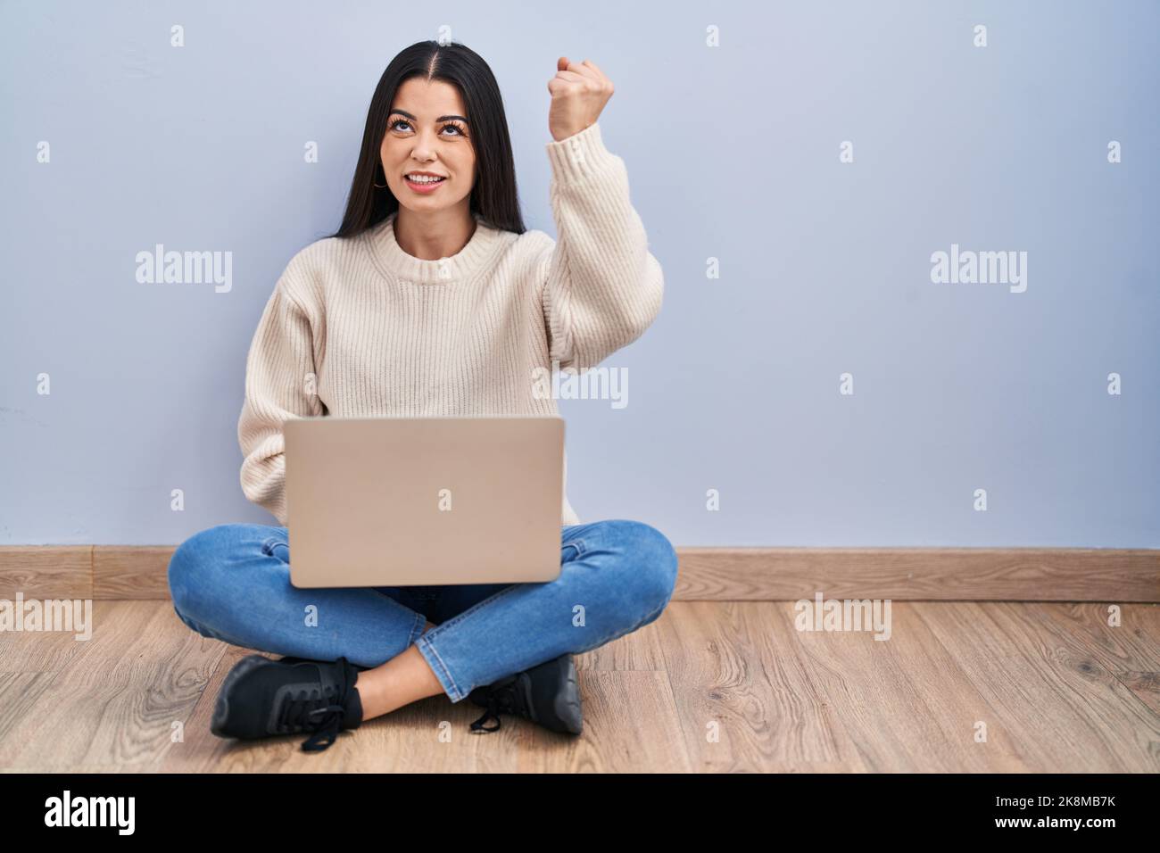 Young woman using laptop sitting on the floor at home angry and mad ...