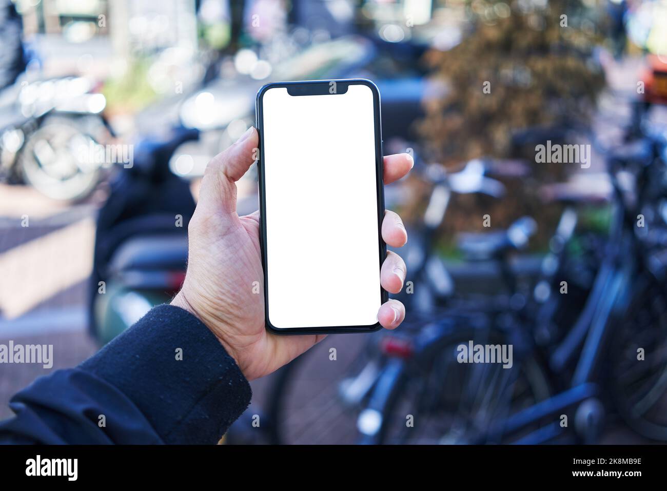 Man holding smartphone showing white blank screen at bike parking Stock Photo - Alamy