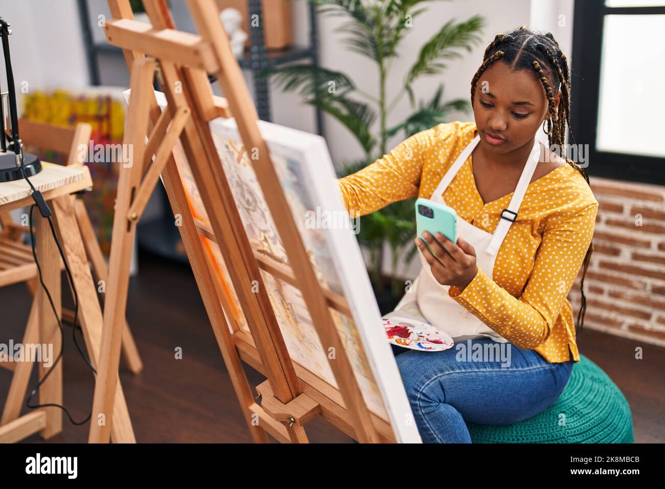 African american woman artist using smartphone drawing at art studio ...