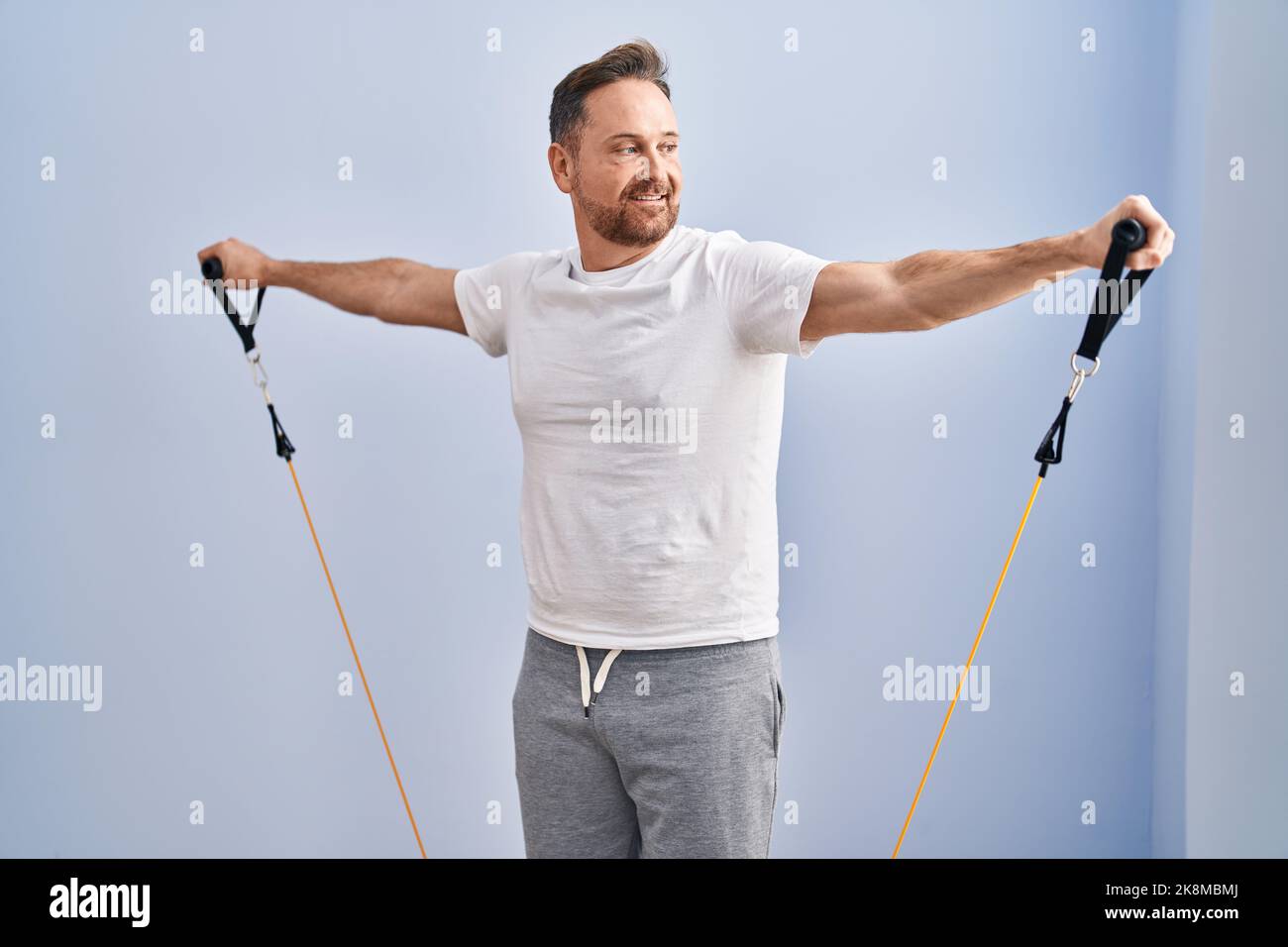 Young caucasian man smiling confident using elastic band training at ...