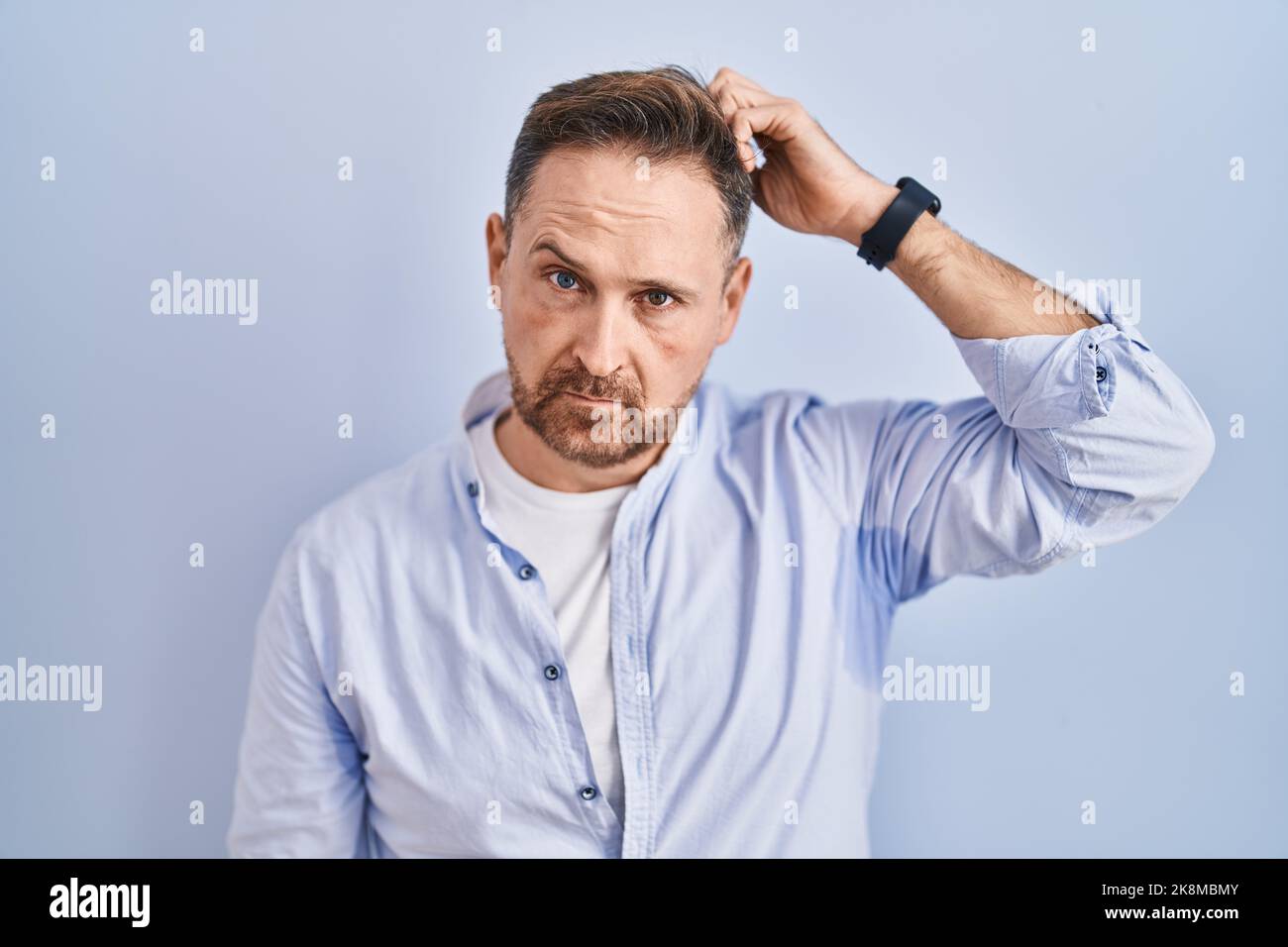 Middle age caucasian man standing over blue background confuse and ...