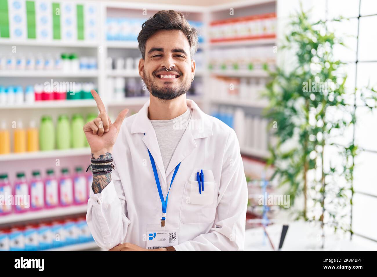 Young hispanic man with tattoos working at pharmacy drugstore smiling ...