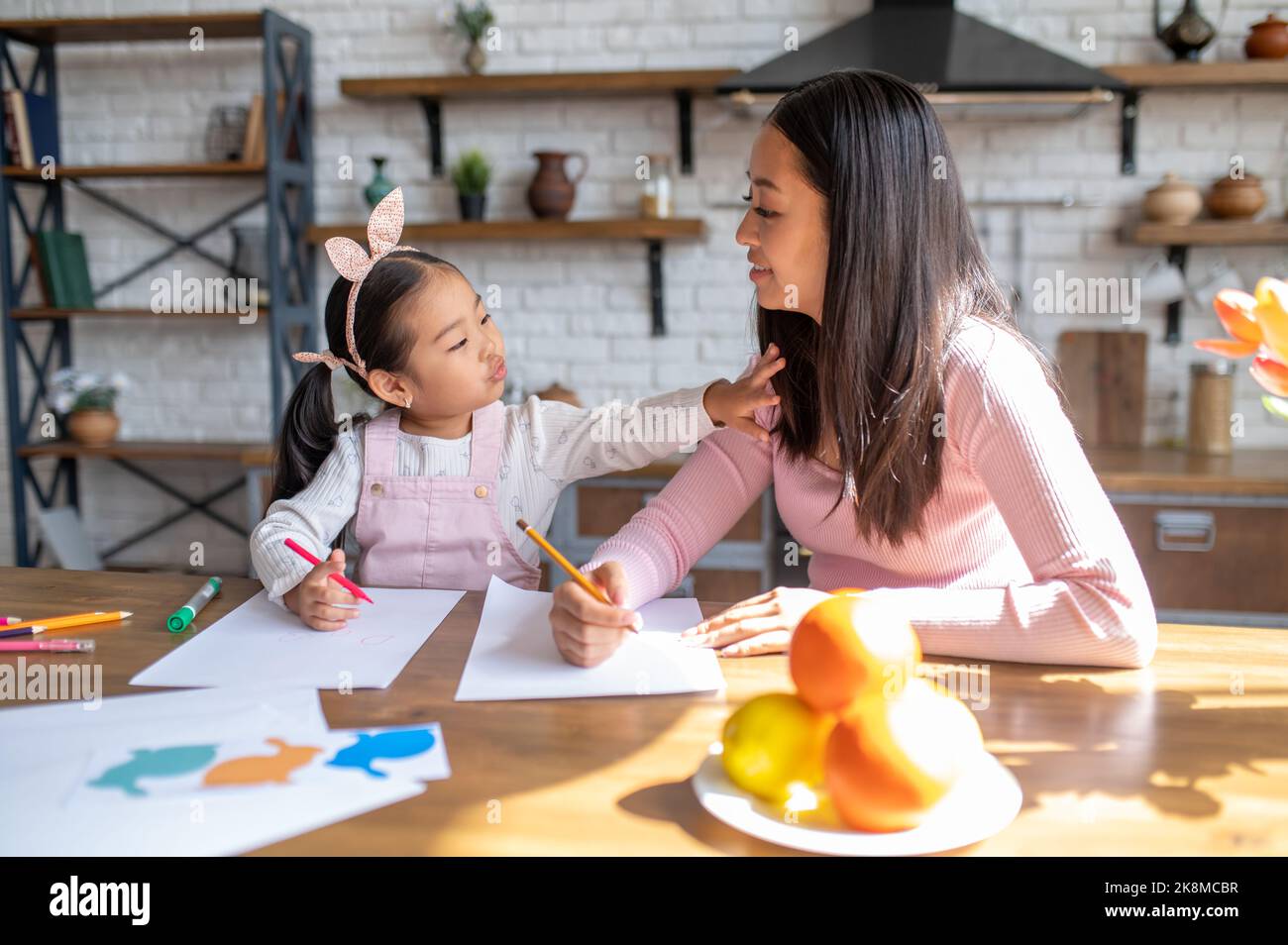 Young female and her child drawing on the paper sheets Stock Photo - Alamy