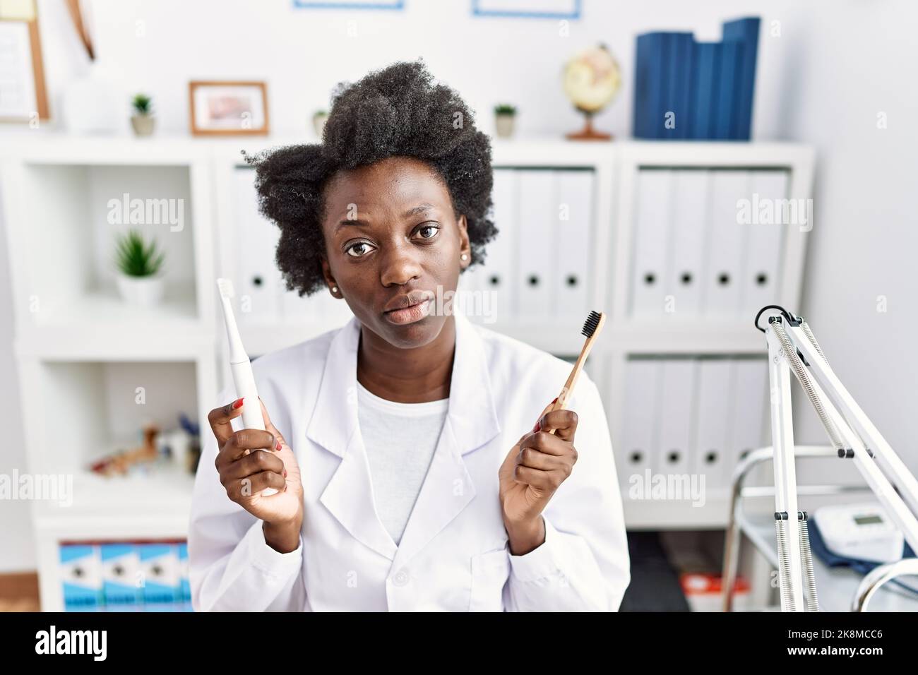 African dentist woman holding electric toothbrush and normal toothbrush ...