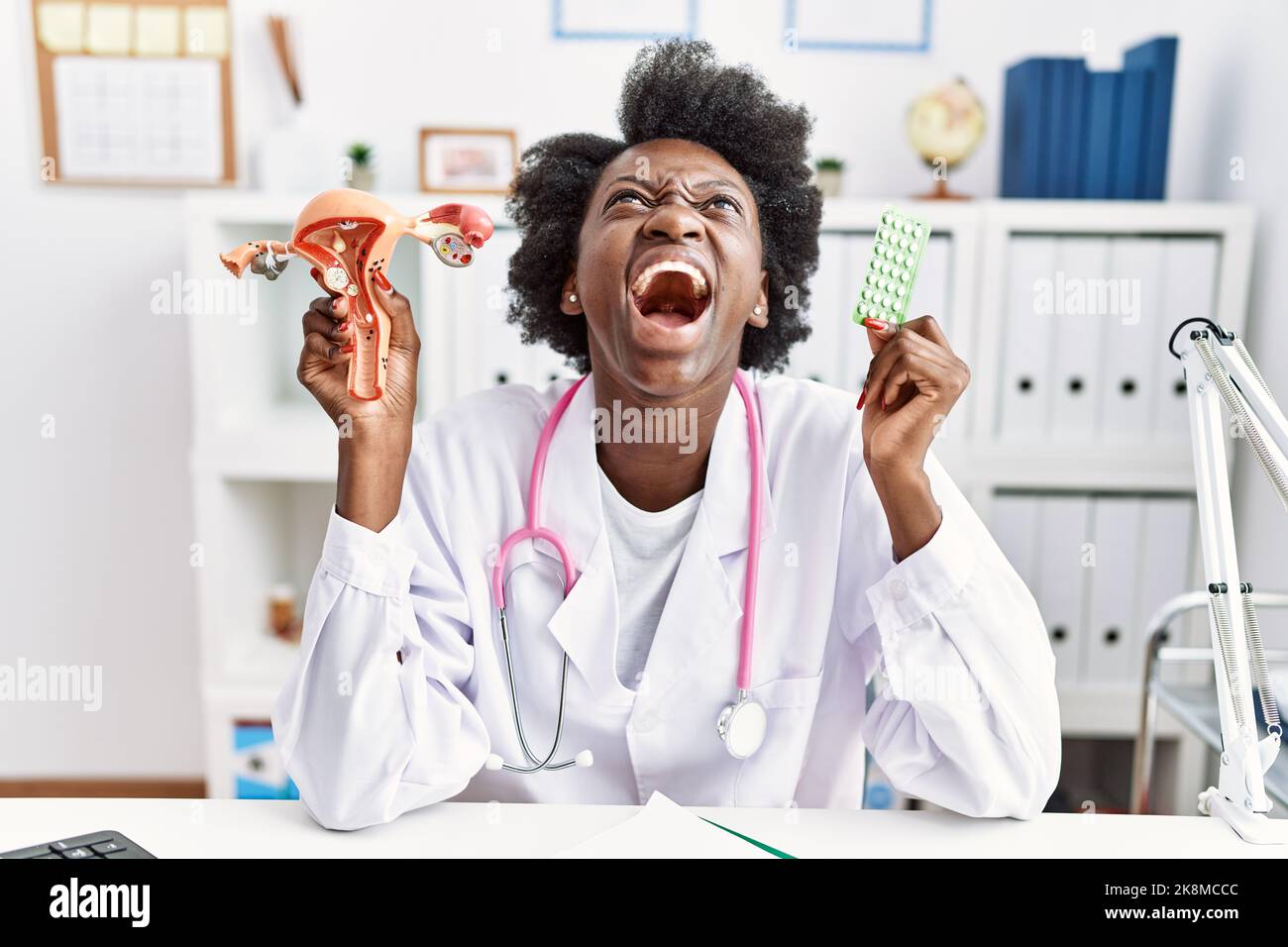 African doctor woman holding anatomical female genital organ and birth ...