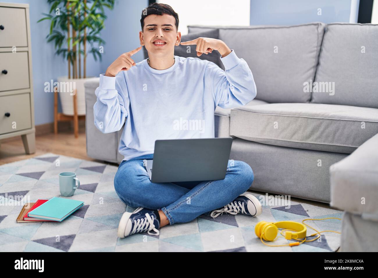 Non binary person studying using computer laptop sitting on the floor ...