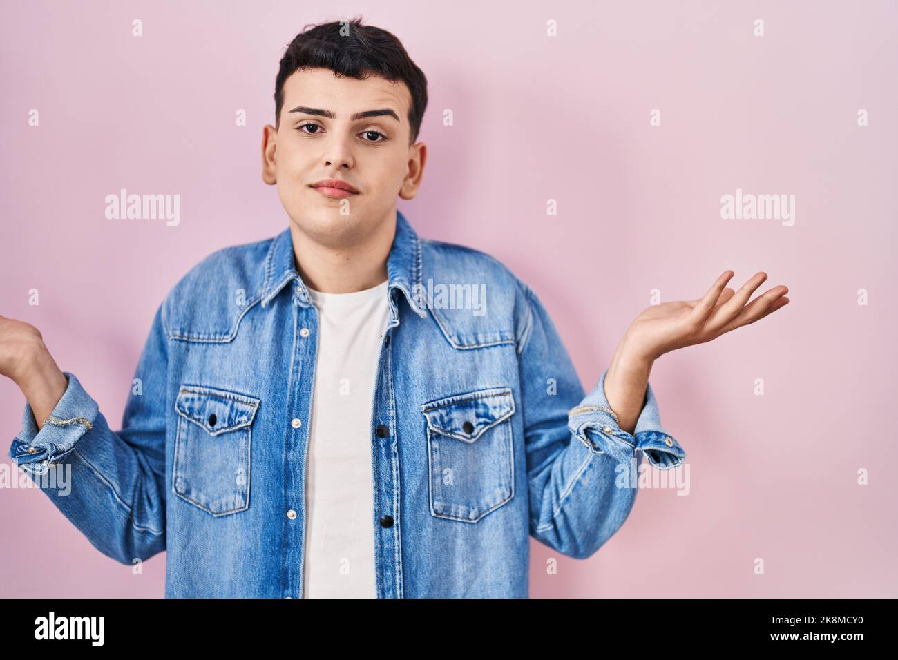 Non binary person standing over pink background clueless and confused ...